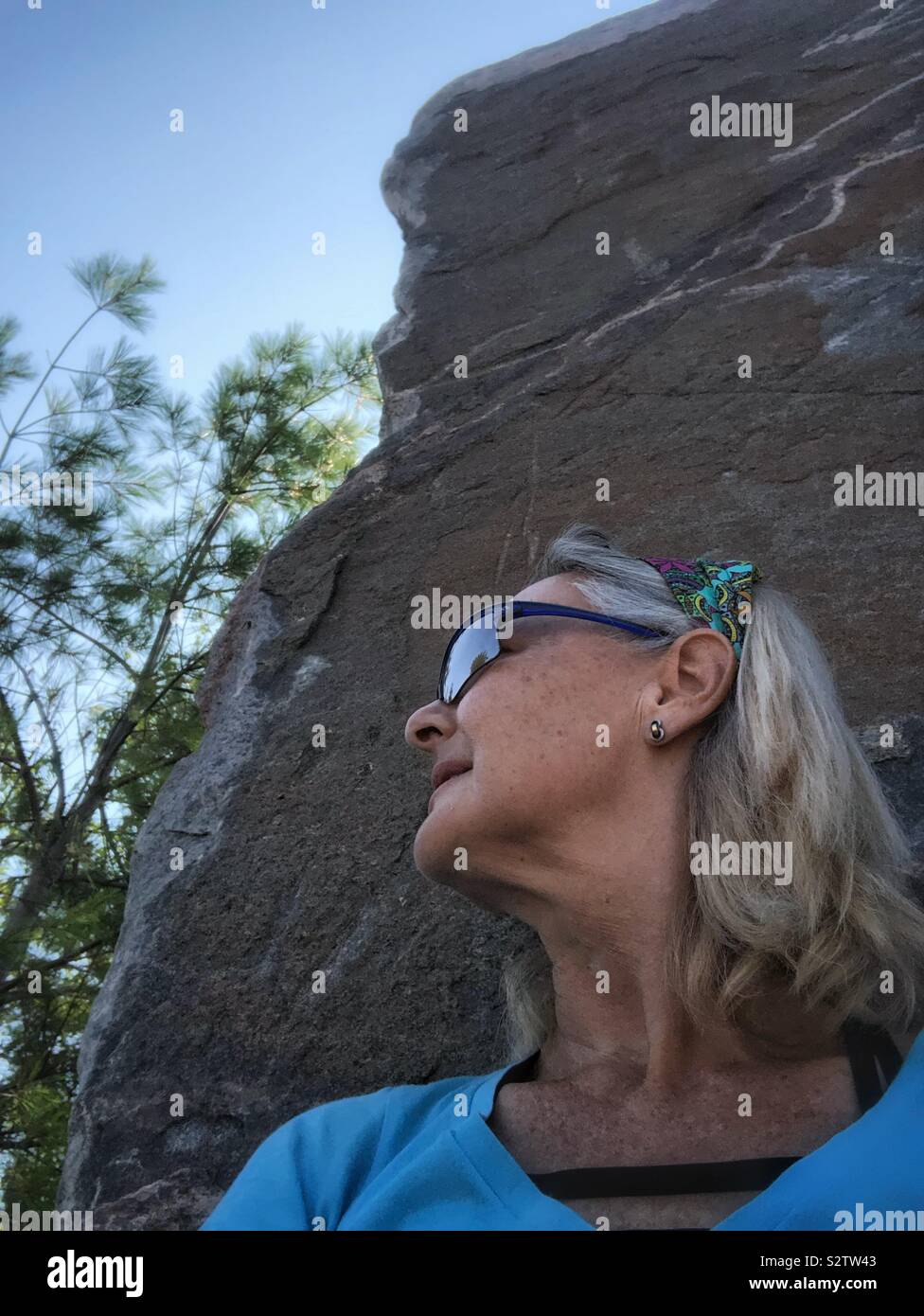 A female leaning against a rock relaxing Stock Photo - Alamy