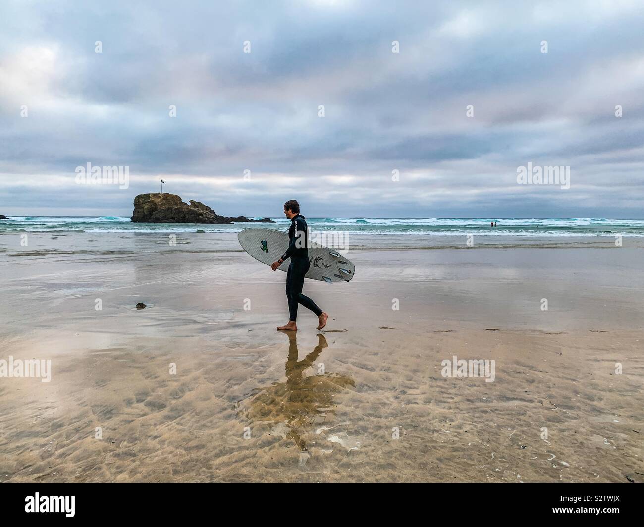 Surfer walking on beach carrying his surfboard in Cornwall Stock Photo ...