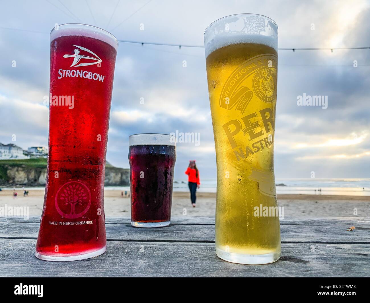 Pint of lager and cider and coke on bench looking out to the beach in ...