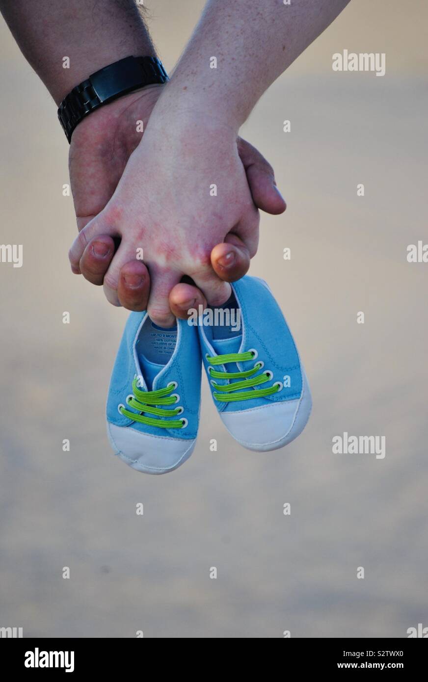 Couple holding baby shoes birth announcement Stock Photo - Alamy