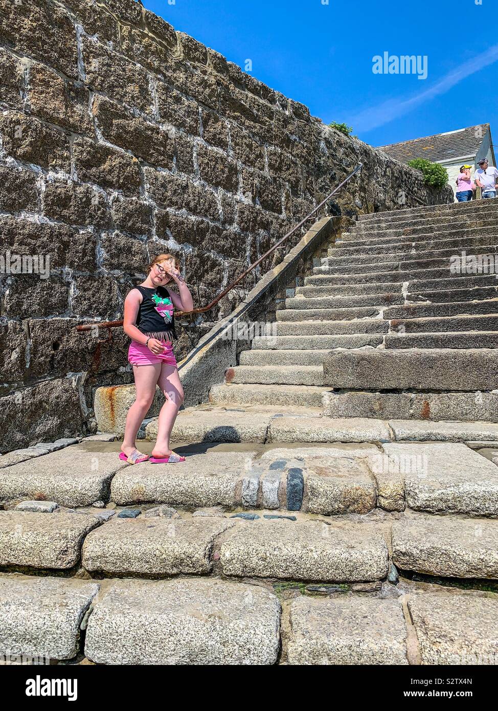 Young girl looking tired walking up steep steps in Marazion Cornwall ...