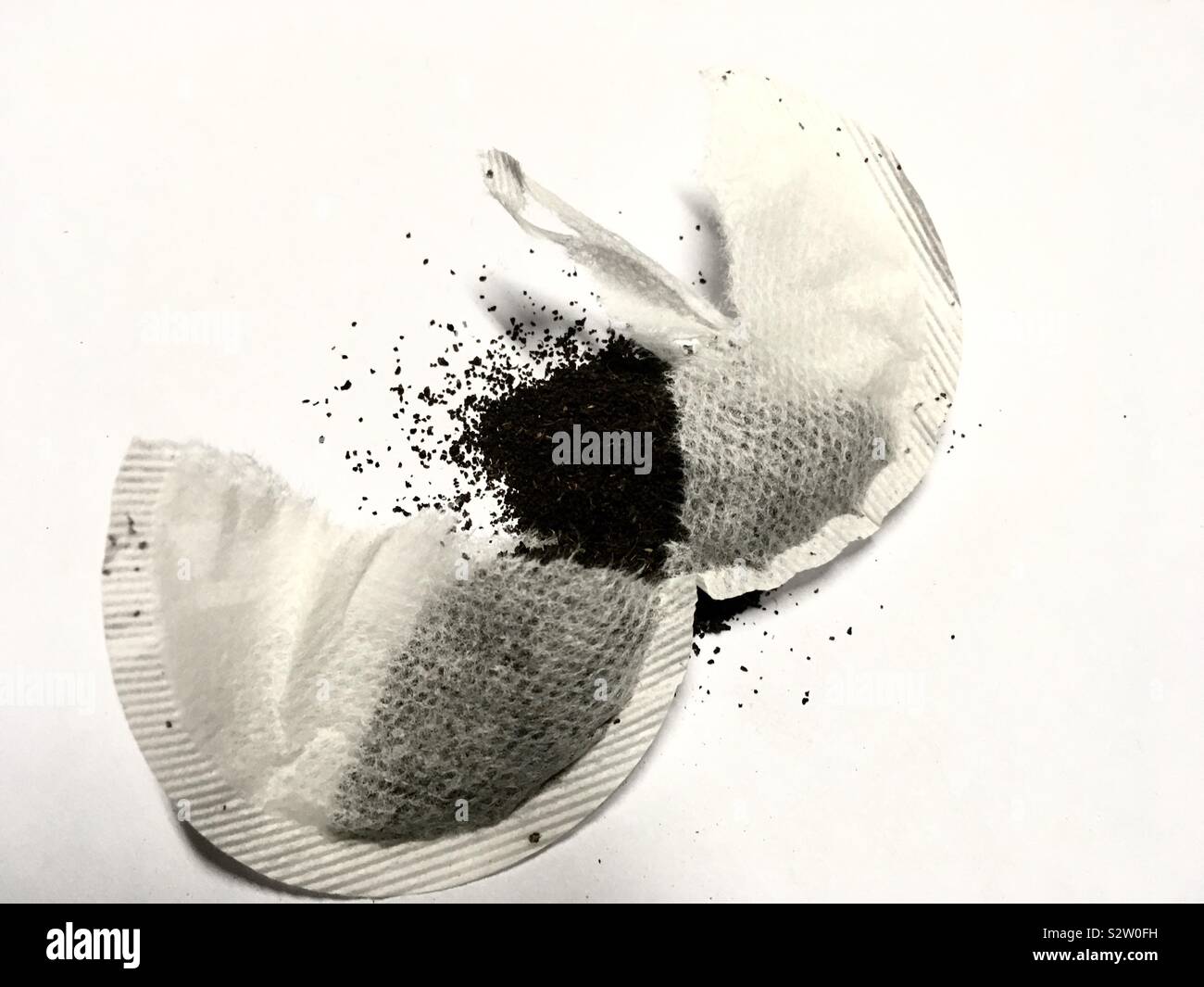 Torn teabag with black tea leaves spilling out Stock Photo - Alamy