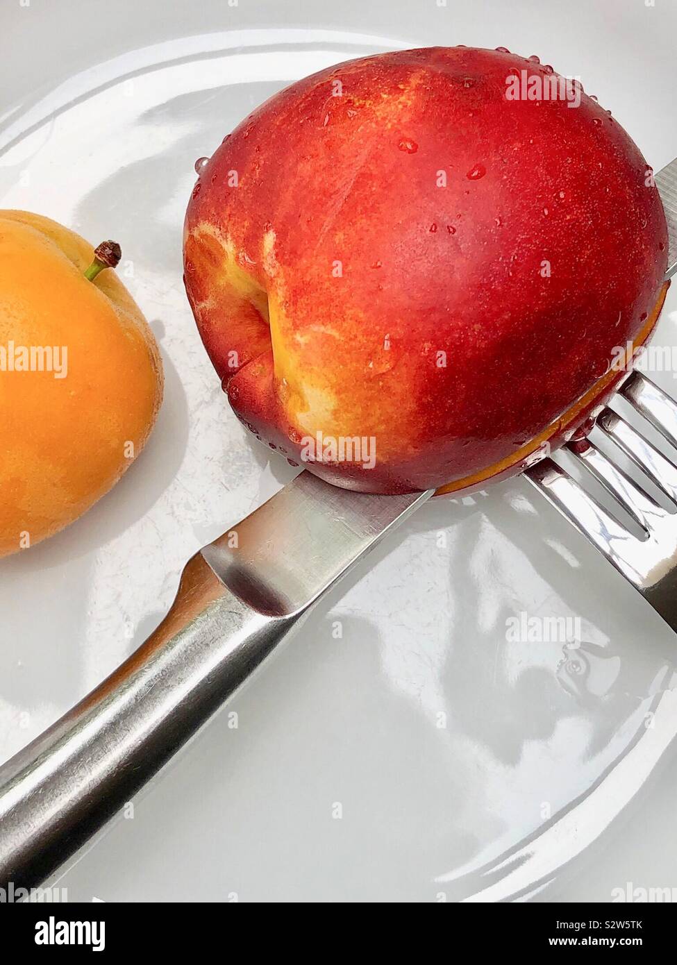 Preparing fruit using a knife and fork Stock Photo - Alamy