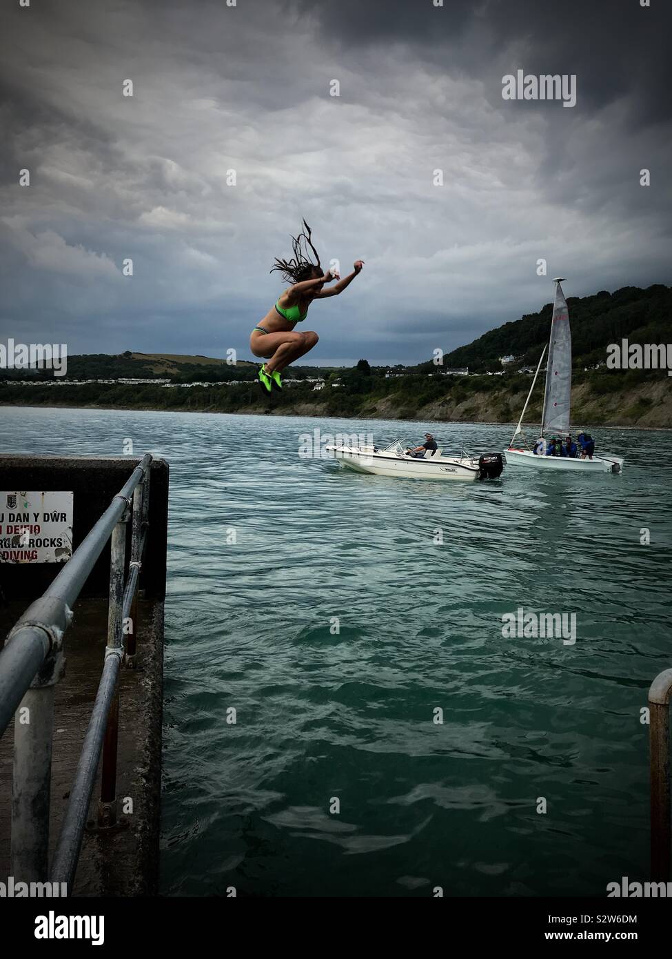 Girl jumping off a harbor into the sea Stock Photo - Alamy