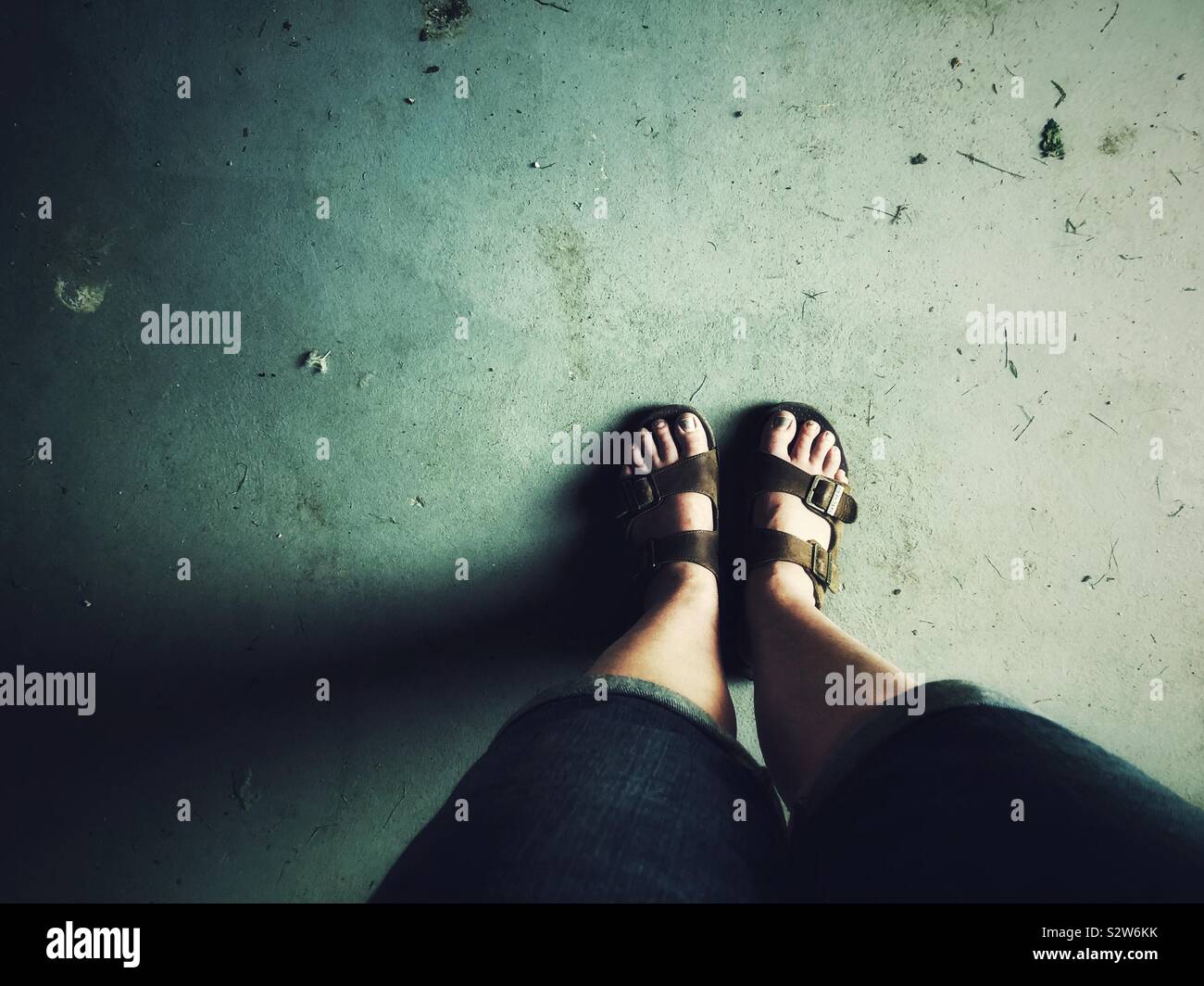 Looking down at woman’s legs and feet wearing denim shorts and brown ...