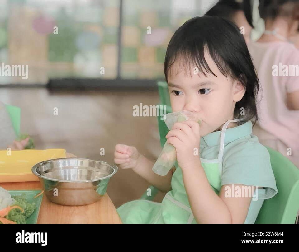 A little girl eating a Vietnamese traditional spring roll that she had ...