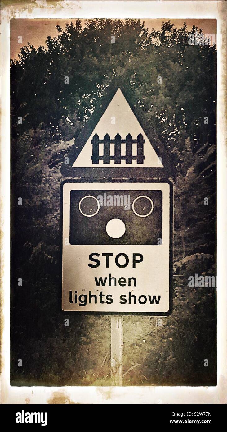 Road sign warning of railway level crossing ahead, saying ‘STOP when ...