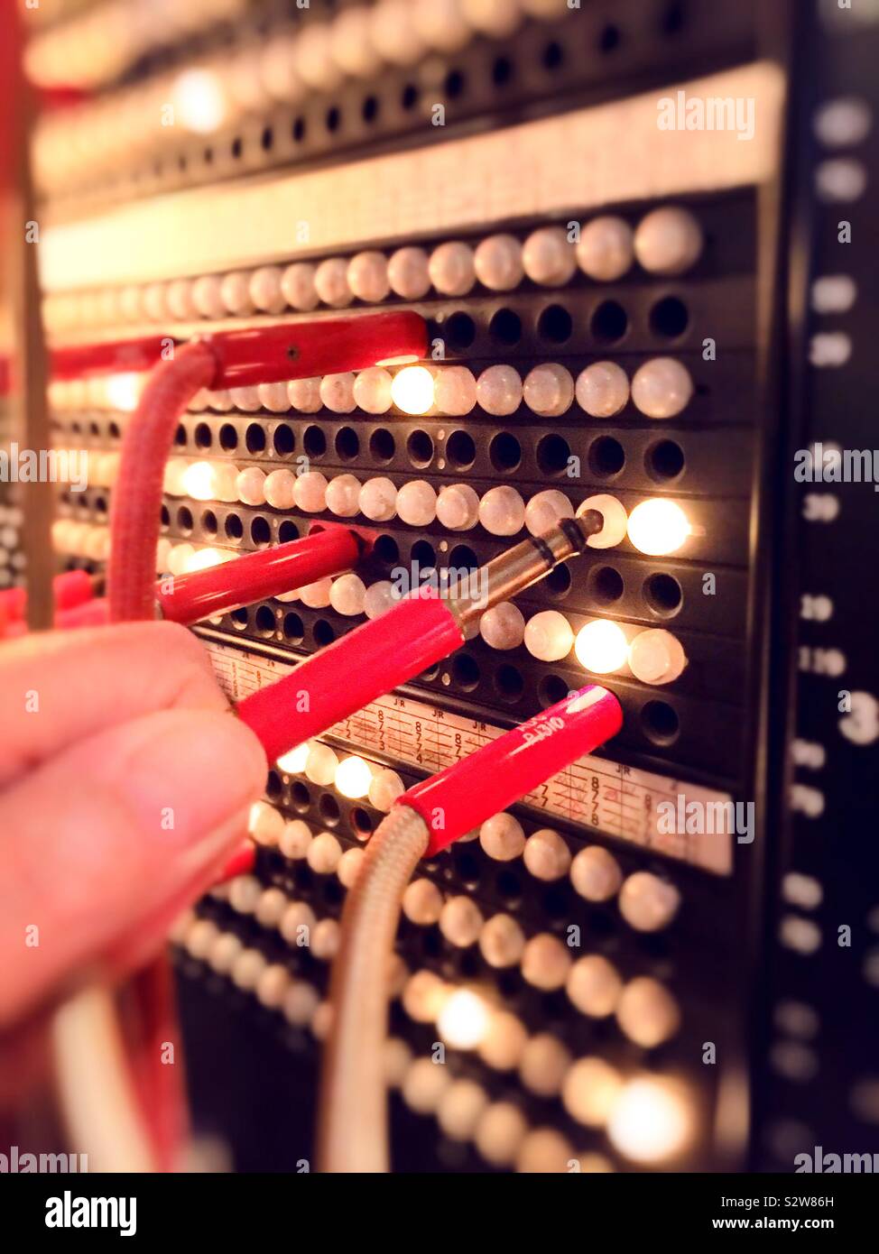 Operator connecting a call on a 1950s vintage switchboard panel, USA ...