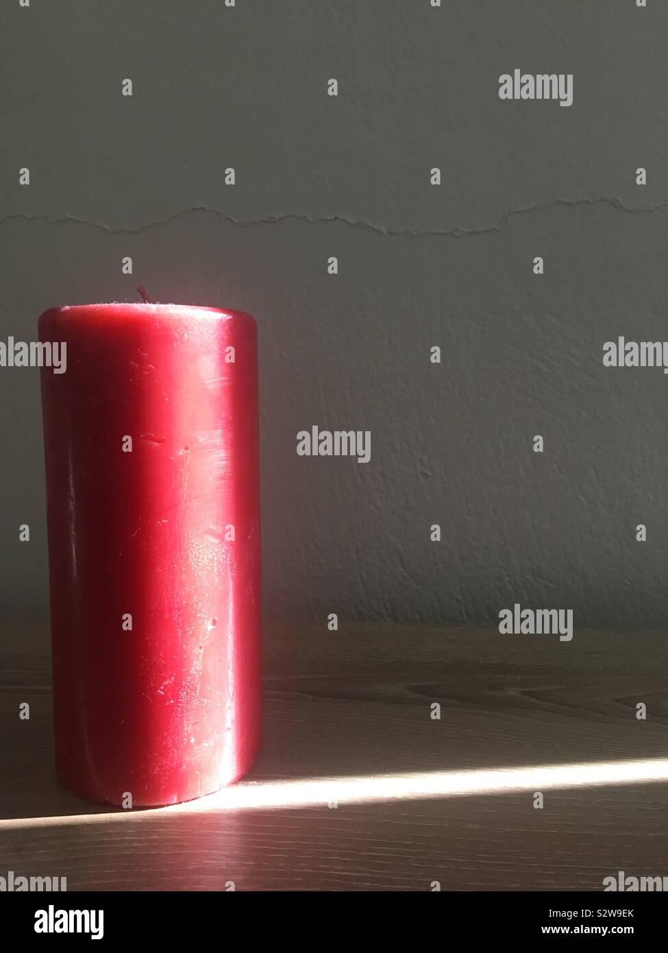 Red candle on table with sunlight Stock Photo - Alamy