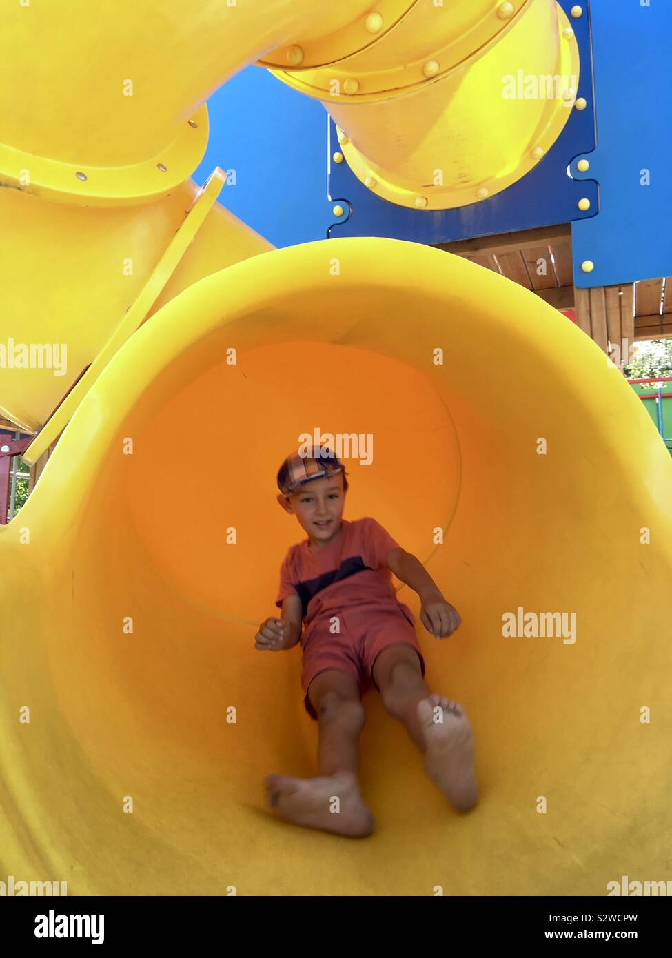 Child sliding in yellow tube slide at playground Stock Photo - Alamy