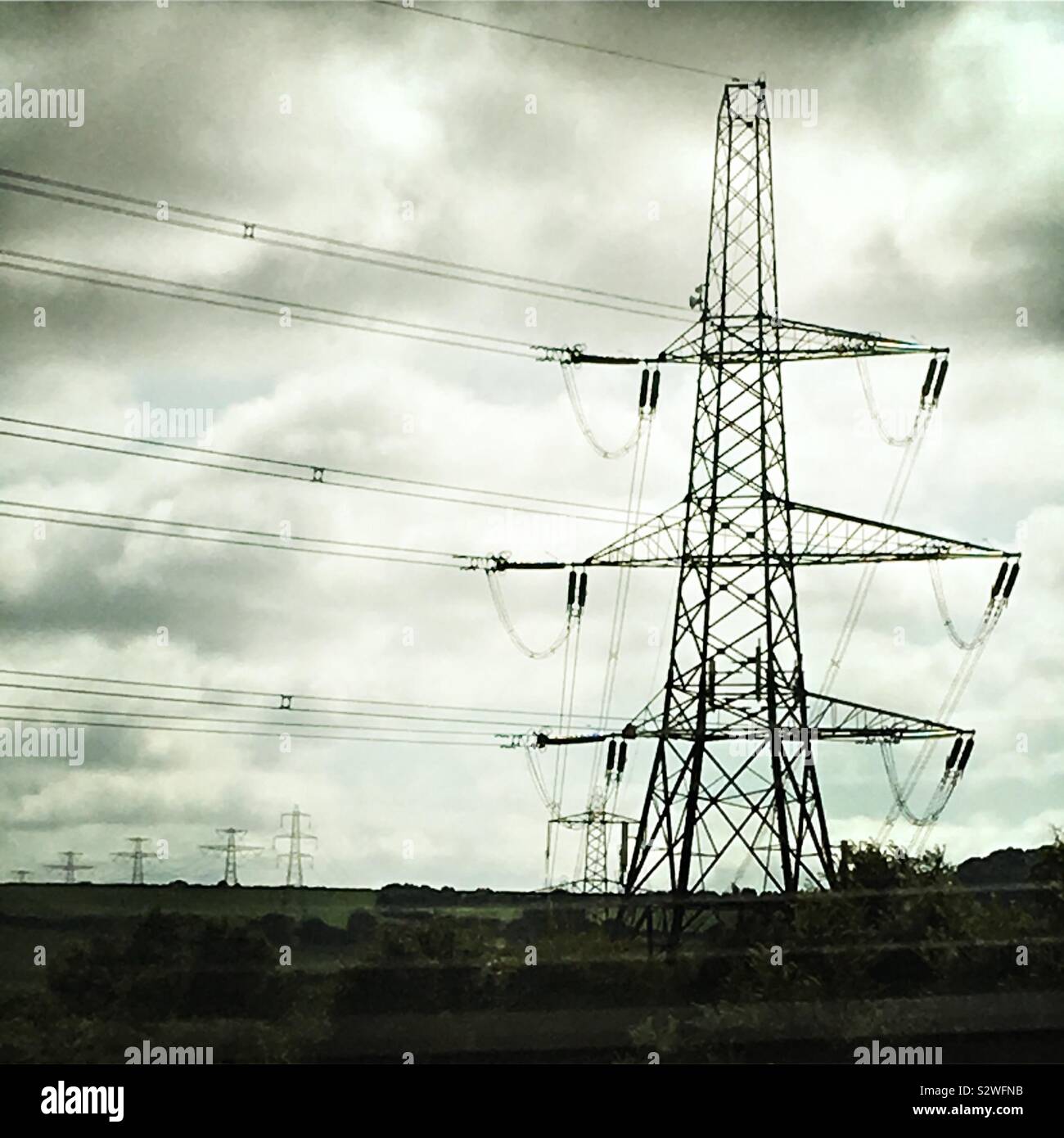 A line of electricity pylons stretching back to the horizon Stock Photo ...