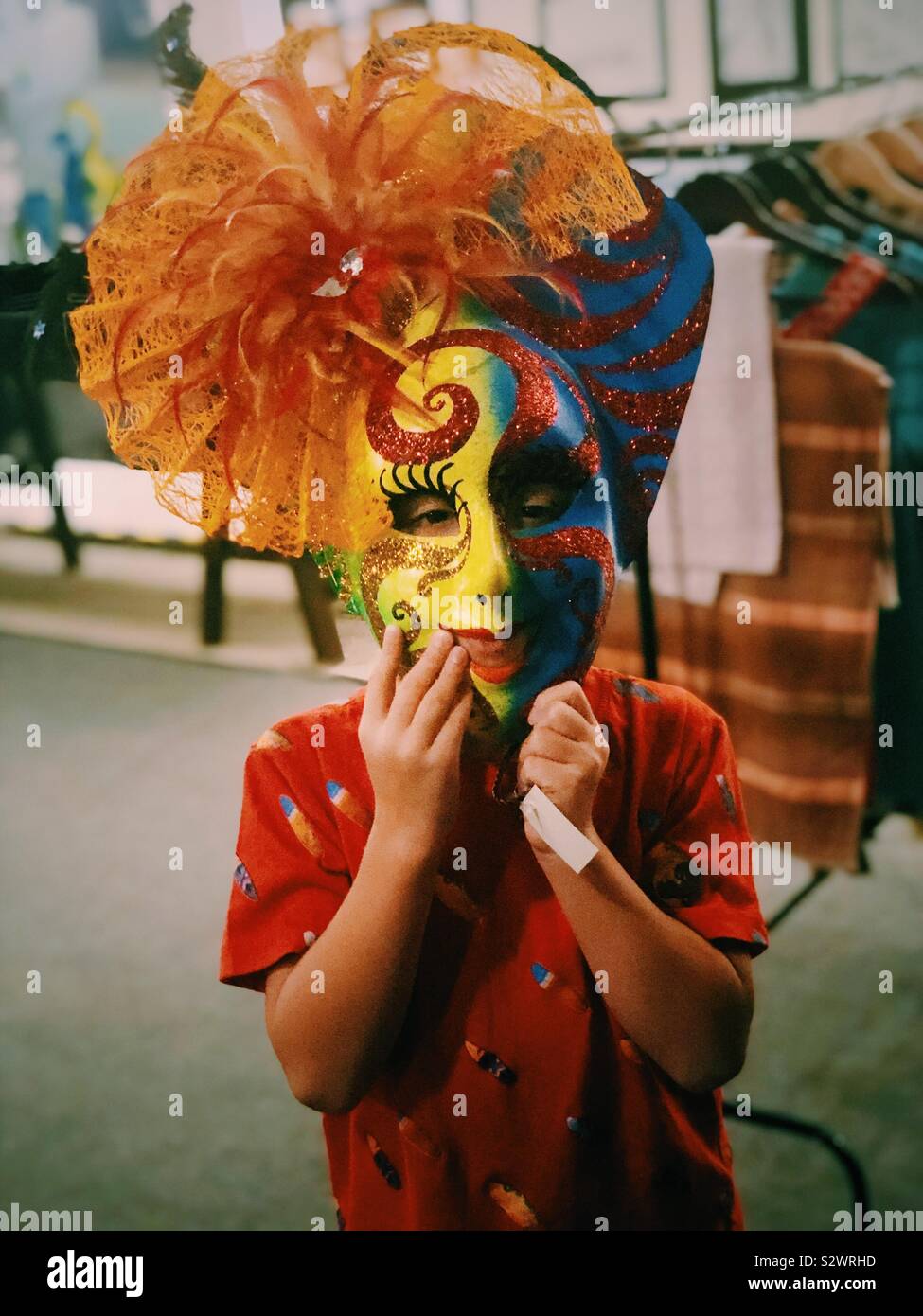 A young child trying on a colourful mask Stock Photo - Alamy