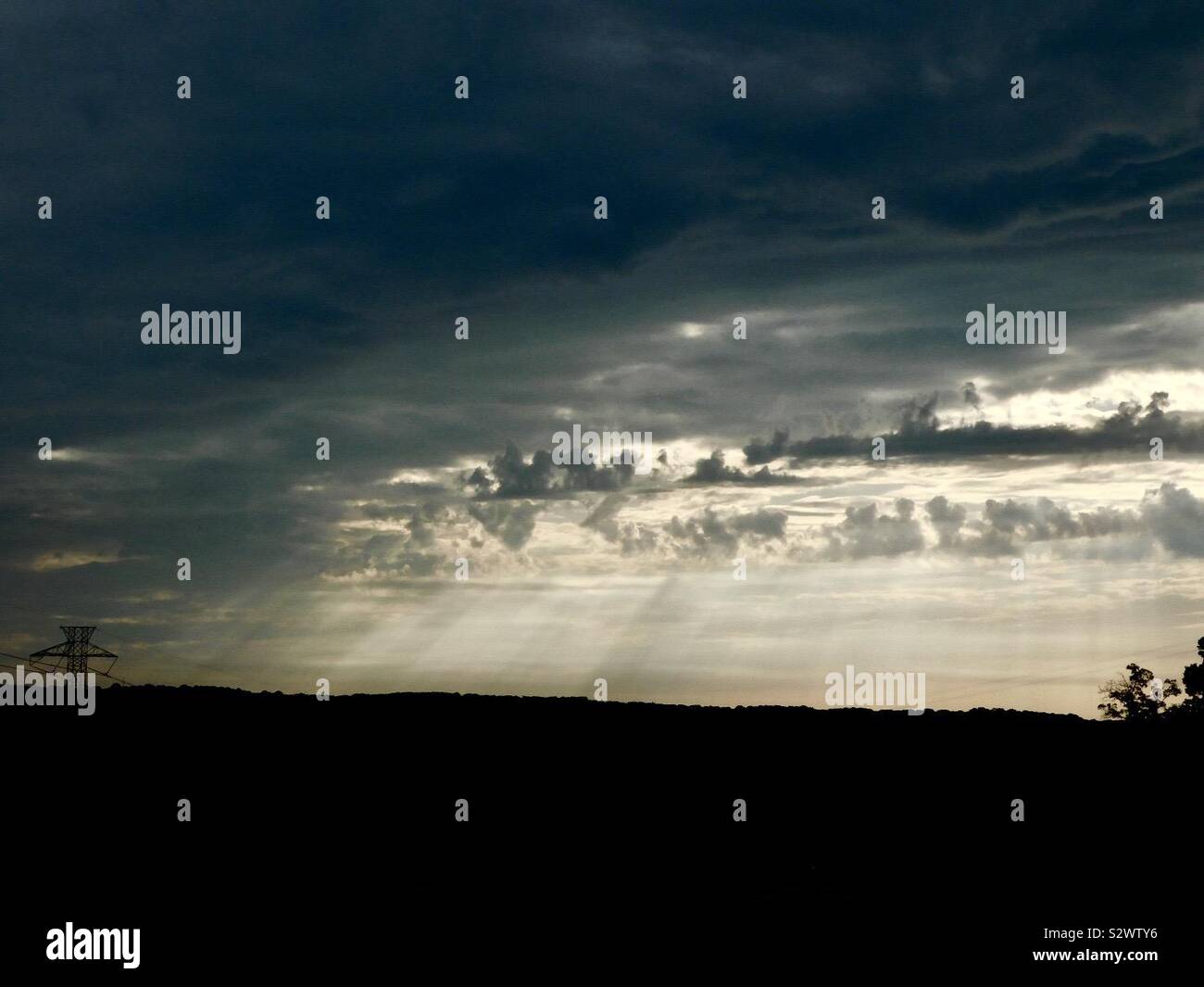 Stunning morning sunrise rays gleaming through dark storm clouds on ...