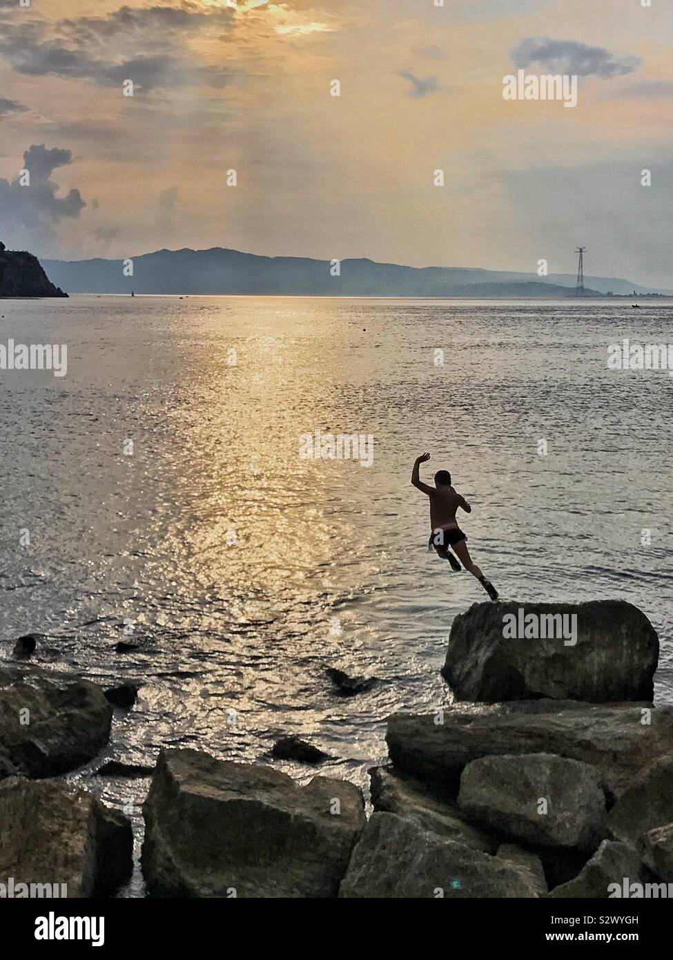 Girl jumping in the water at sunset Stock Photo - Alamy