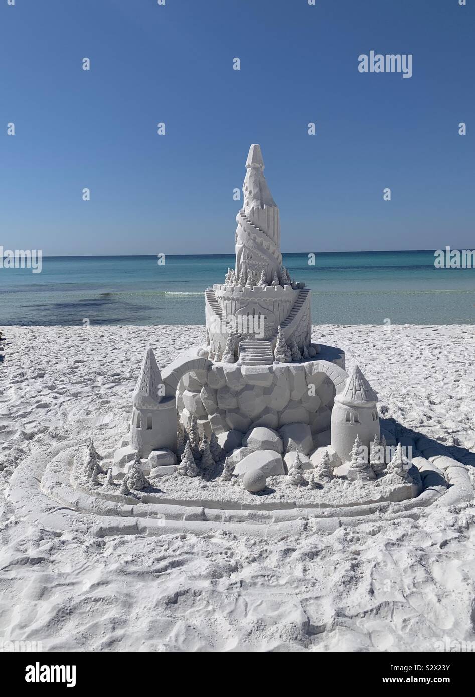 Large detailed sandcastle on white sand beach with view of turquoise ...