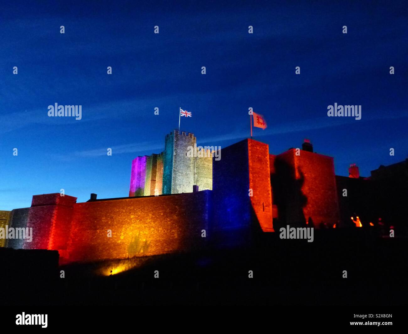 Dover castle lit up with coloured spot lights at night with a sky dark ...