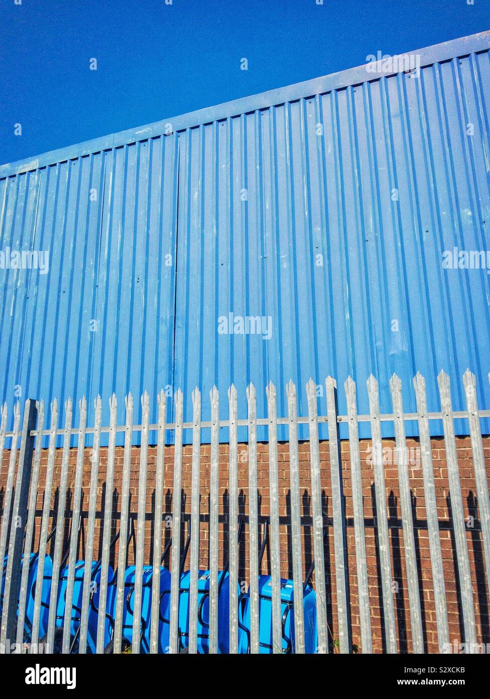 Side of blue metal building with security fence Stock Photo - Alamy