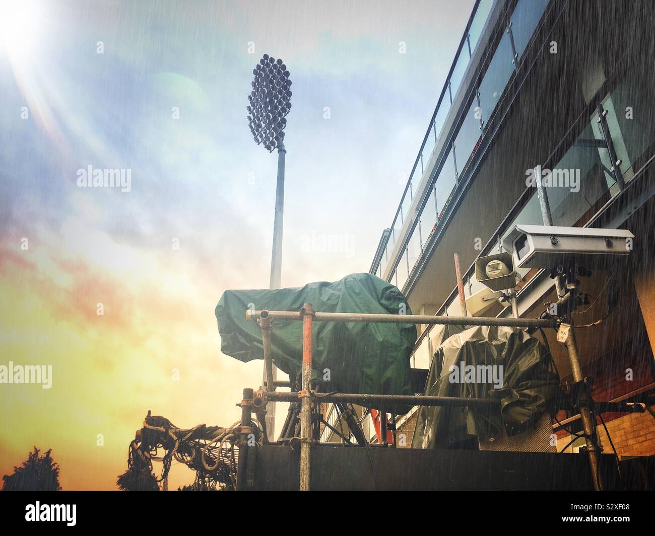 Sports broadcast tv camera covered from the rain under a floodlight at ...