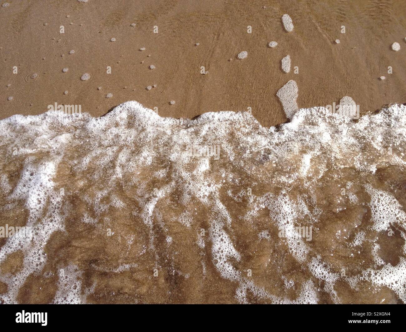 Sea and sandy beach with water waves over the sand Stock Photo - Alamy