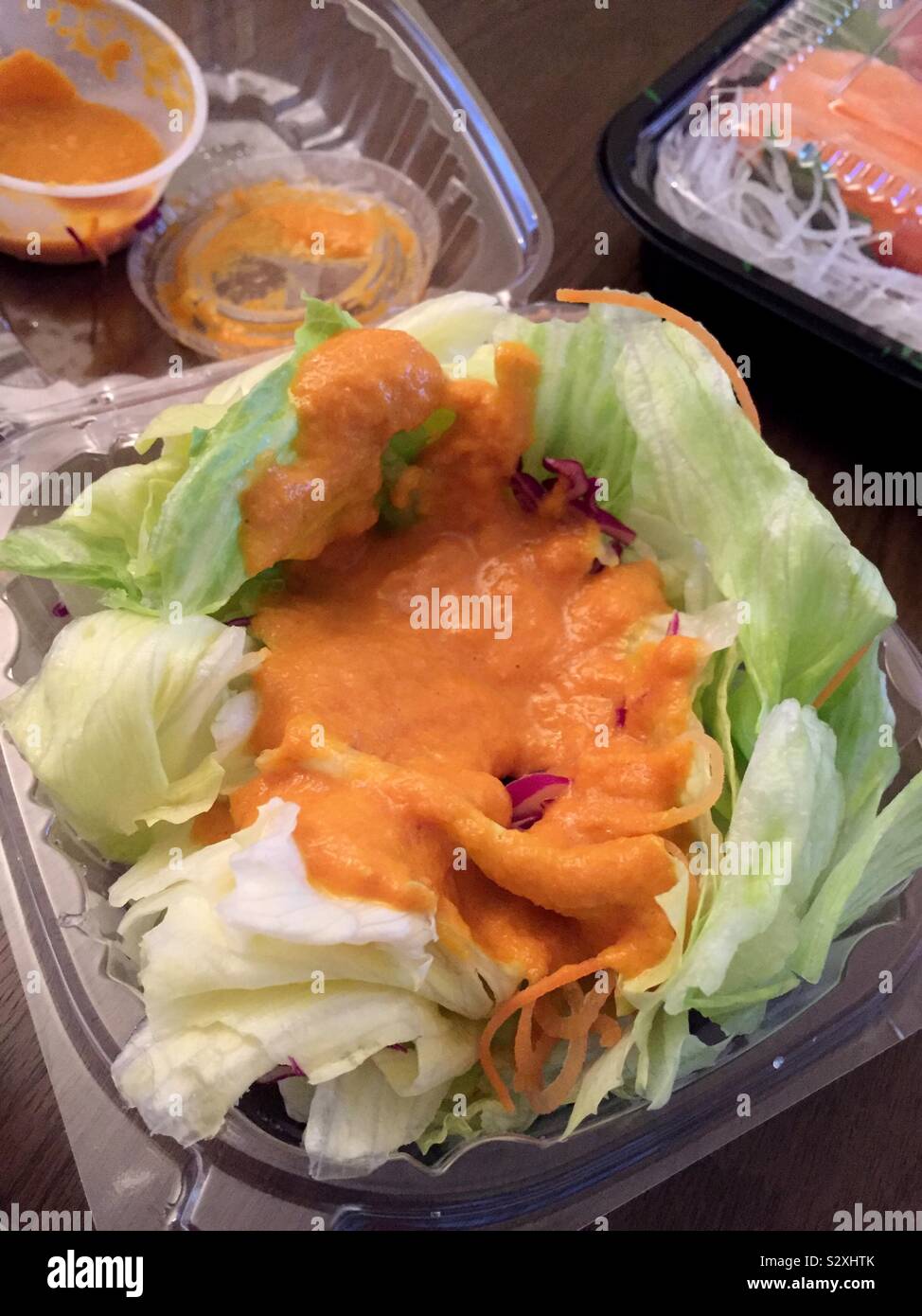 Iceberg lettuce with dressing in a delivery plastic container, USA ...