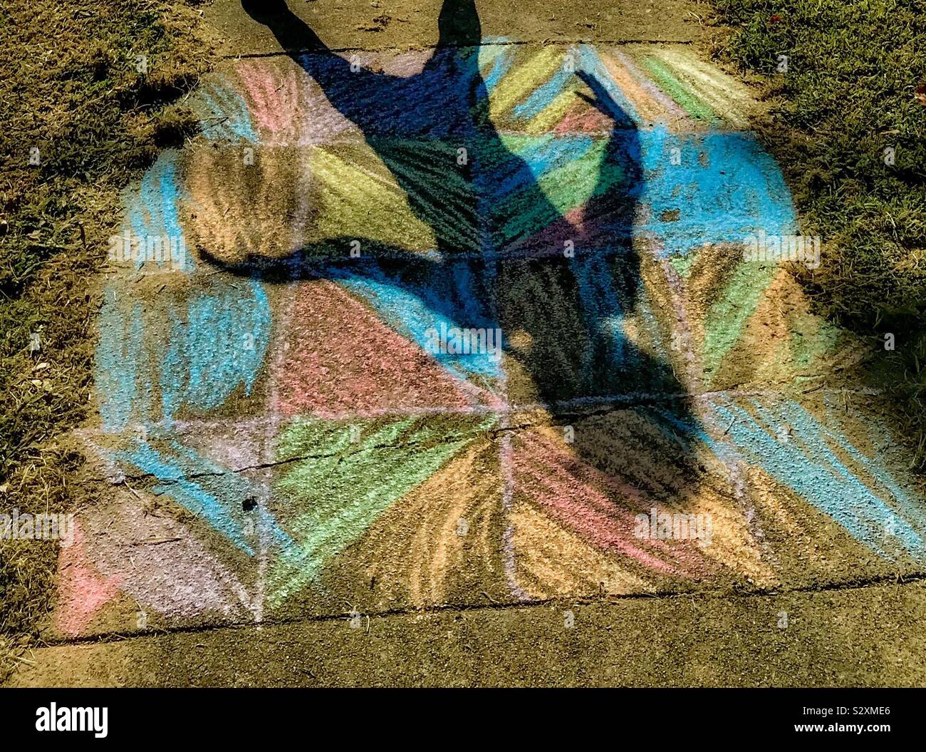 Little girl leaves a shadow on multicolored chalk drawing on sidewalk ...