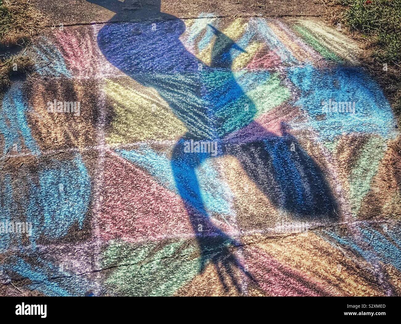 Child casts dramatically posed shadow across multicolored chalk drawing ...