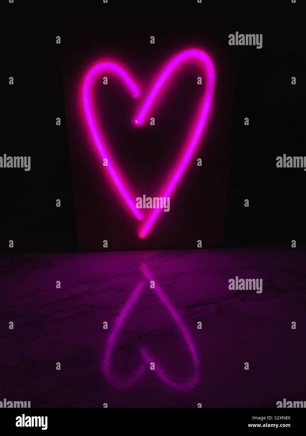 Pink Neon heart lighted up in the dark Stock Photo - Alamy