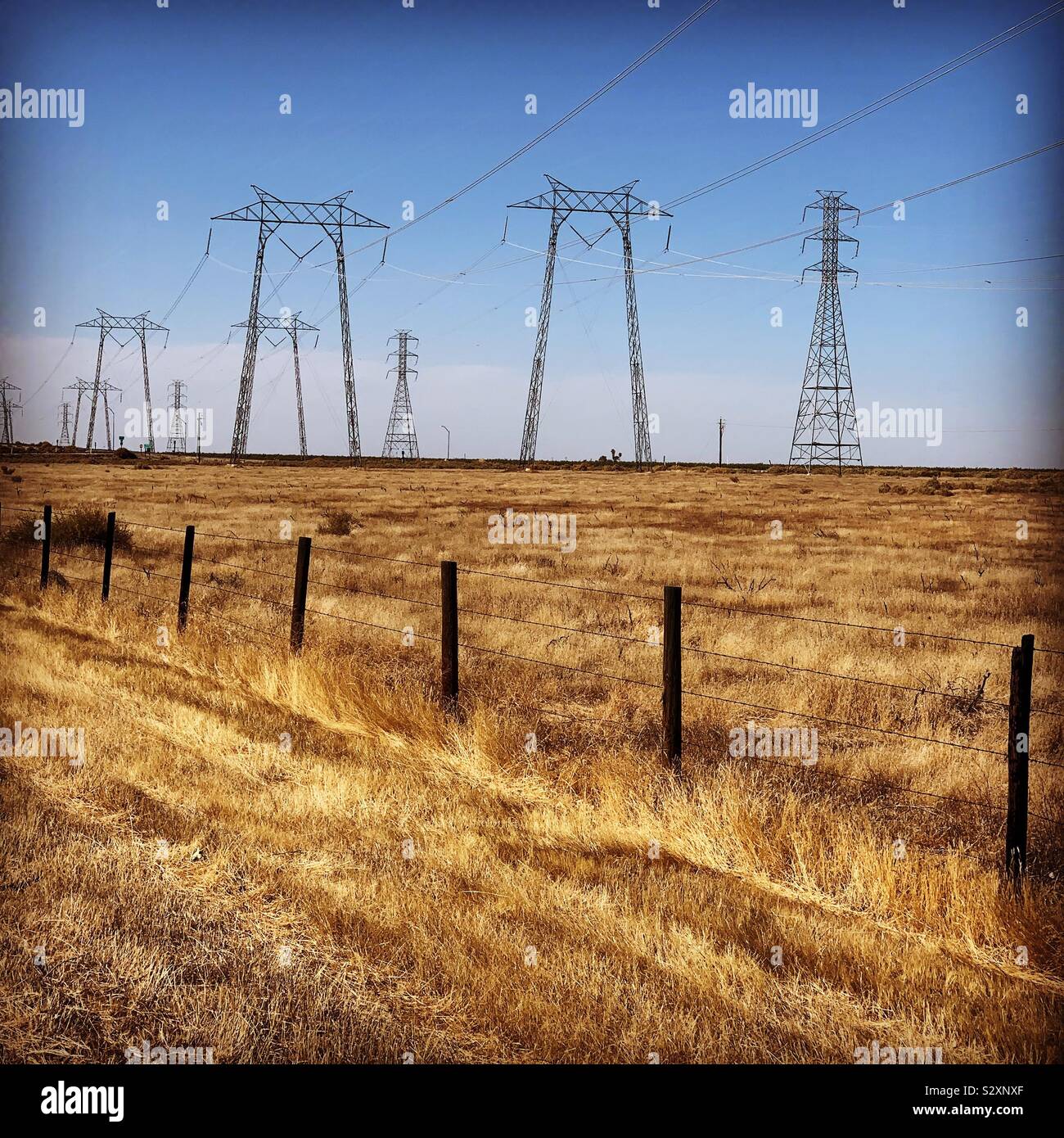Transmission towers on a flat landscape behind a fence Stock Photo - Alamy