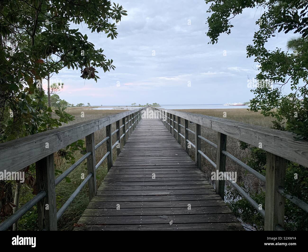 Long wooden pier leading to bay water with evening skies Stock Photo ...