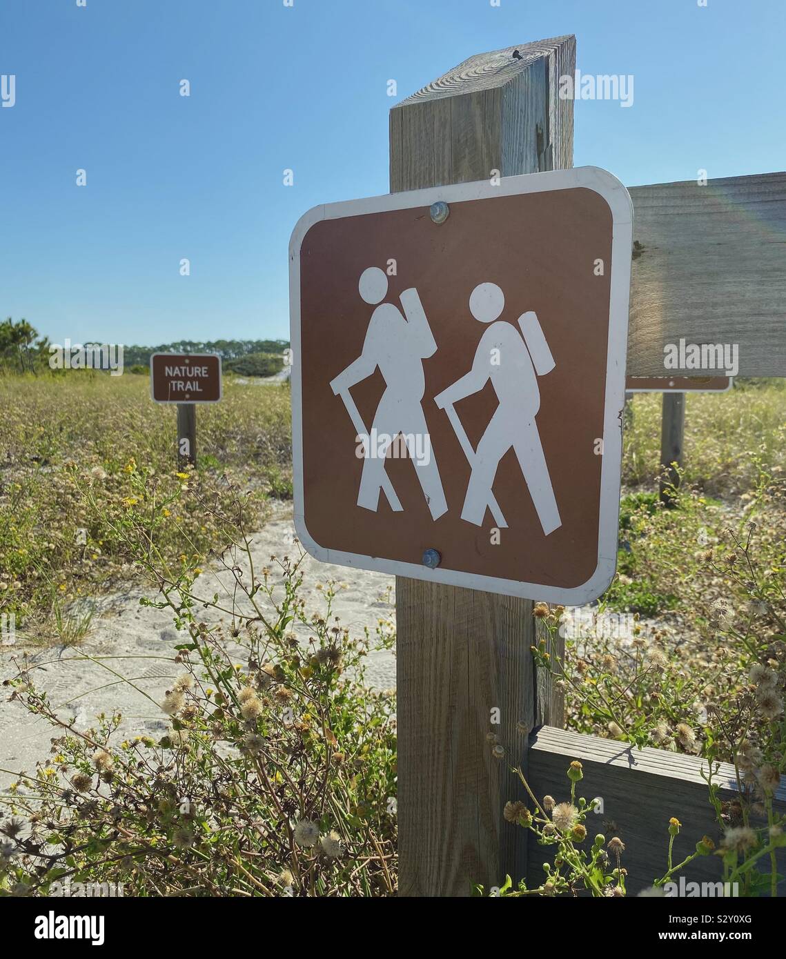 Hiking sign entering a nature trail with symbols on the sign of people ...