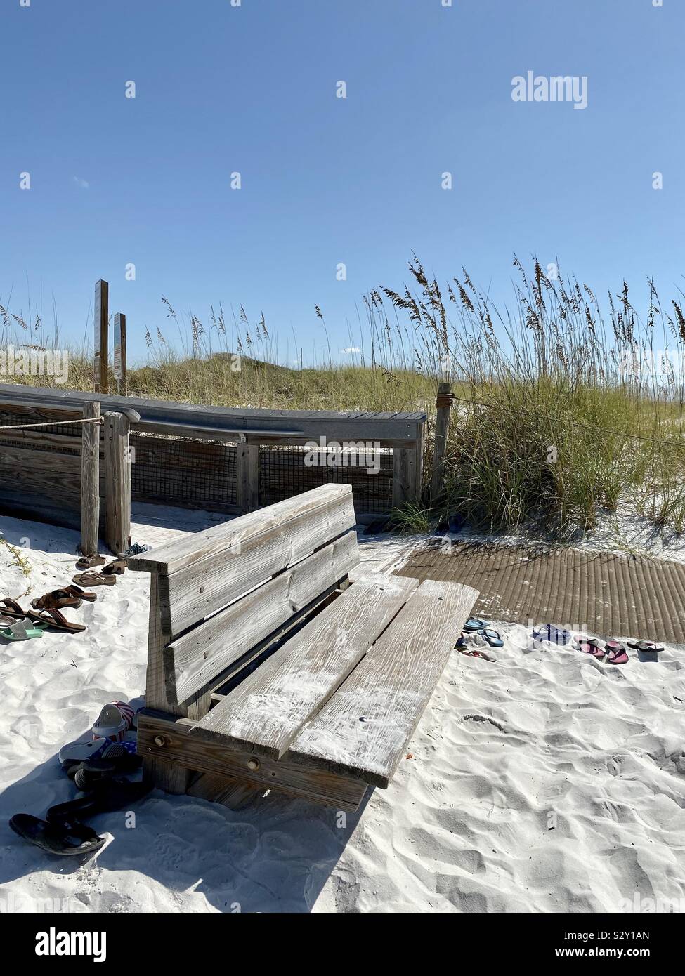 Setting bench on white sand beach with shoes setting around it Stock ...