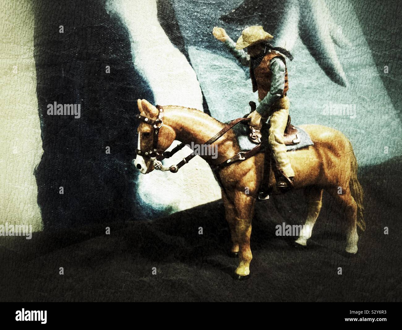 Grunge photo of toy horse and cowboy figures posed in front of abstract ...