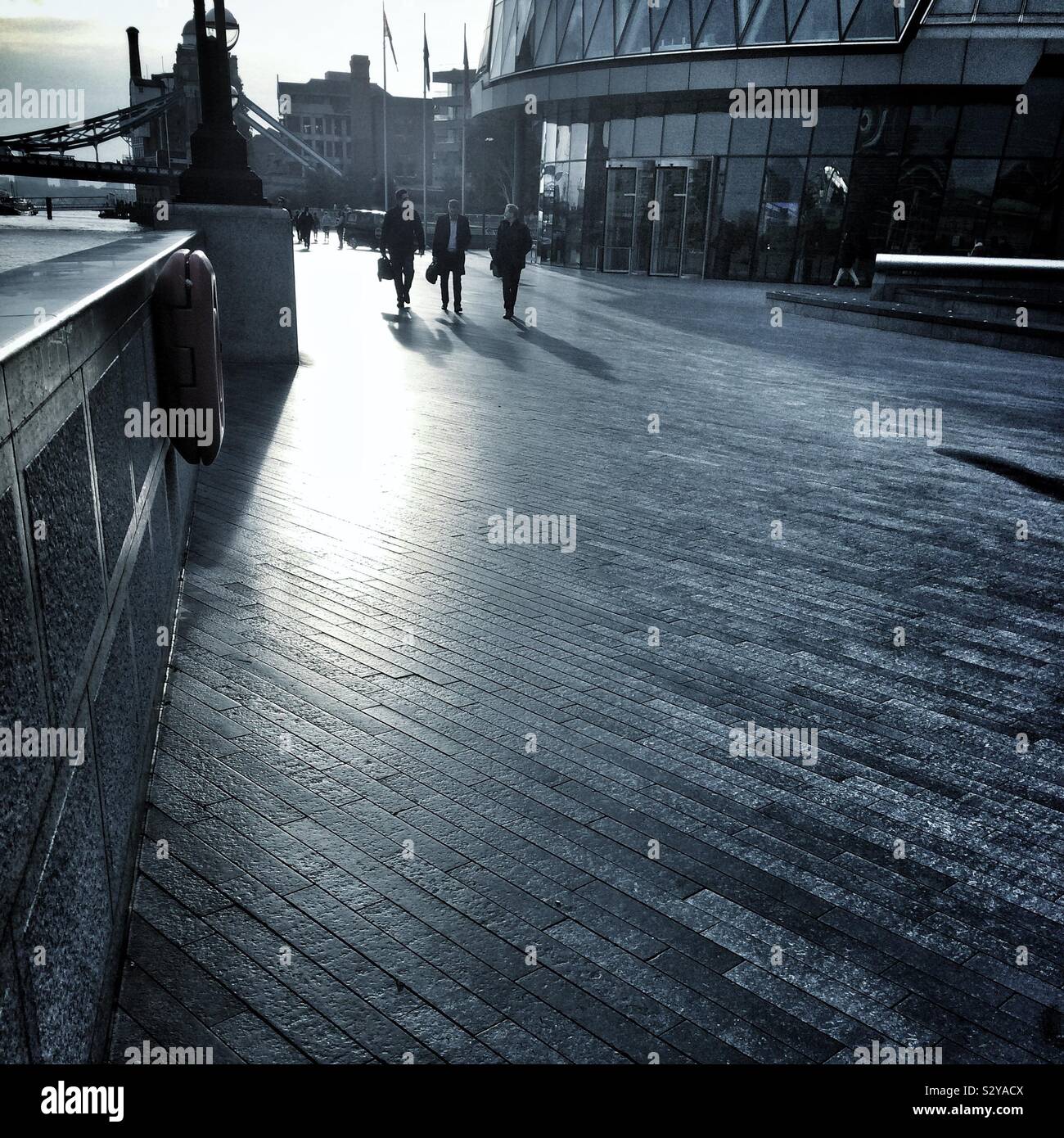 Three people walk casting shadows with their backs to the morning sun ...