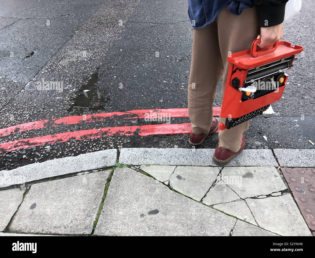 Man holding a red portable typewriter in hand Stock Photo - Alamy