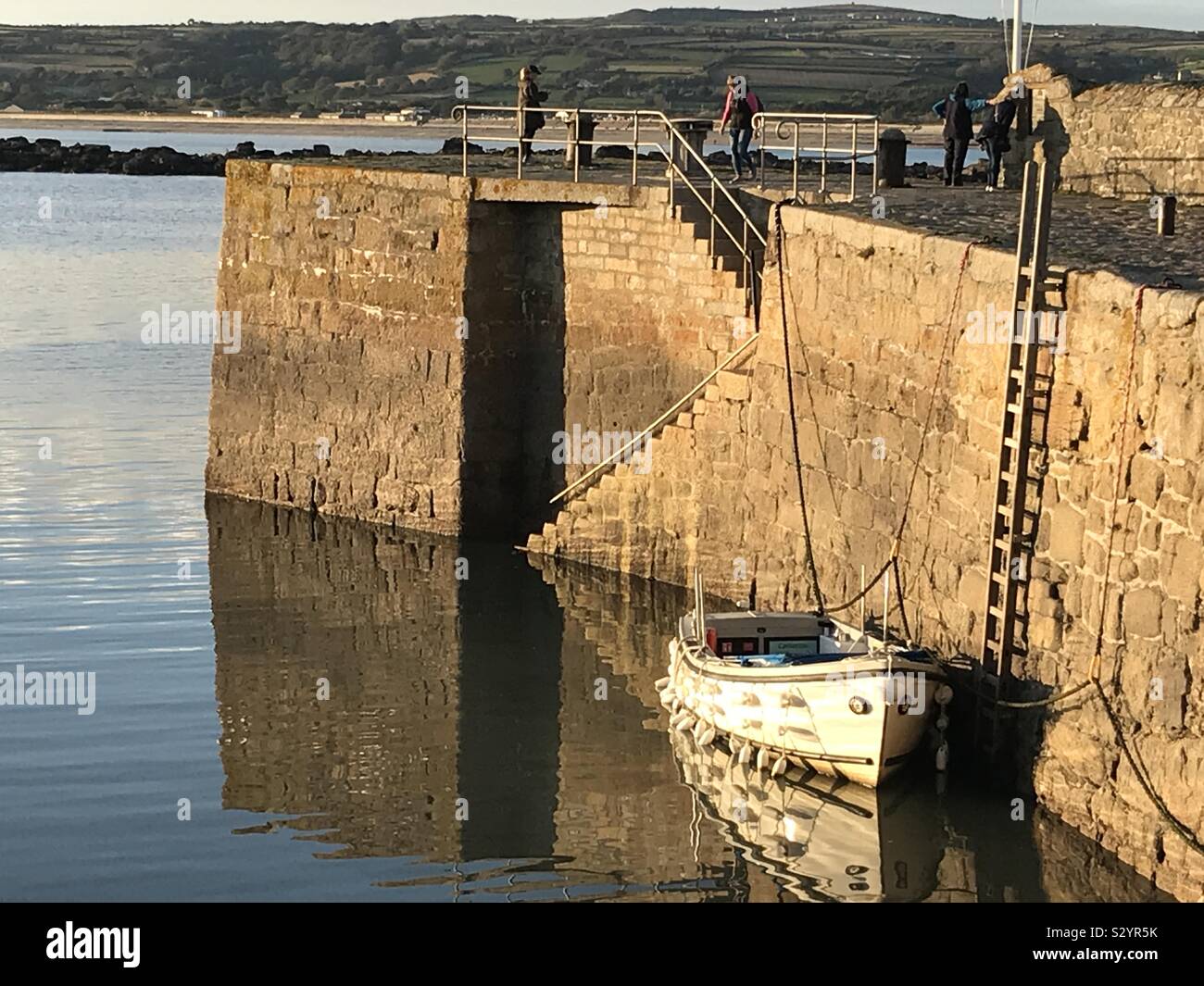 Boat by harbour wall Stock Photo - Alamy