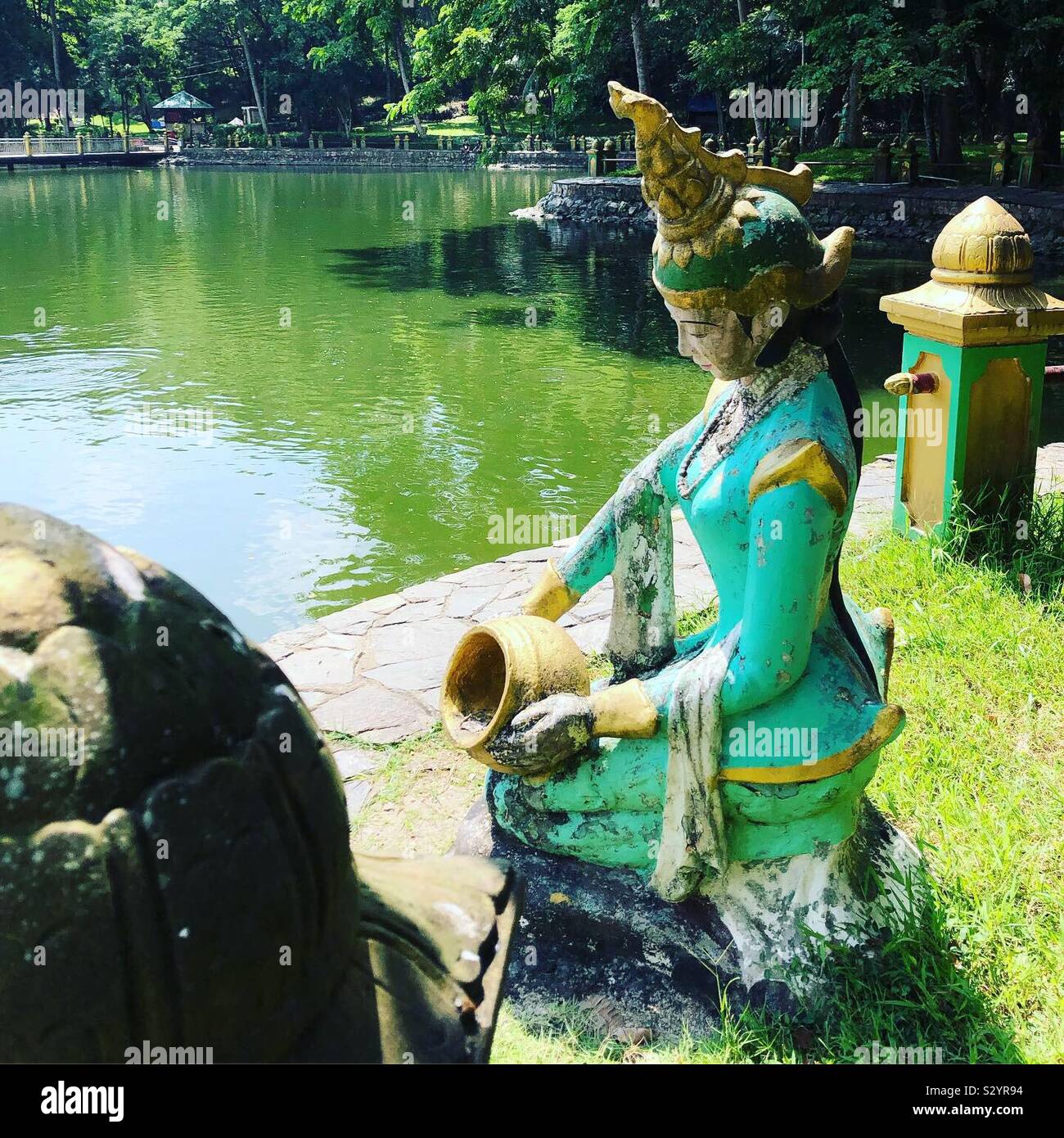 An ancient statue next to a pond in a park in Yangon, Myanmar Stock ...