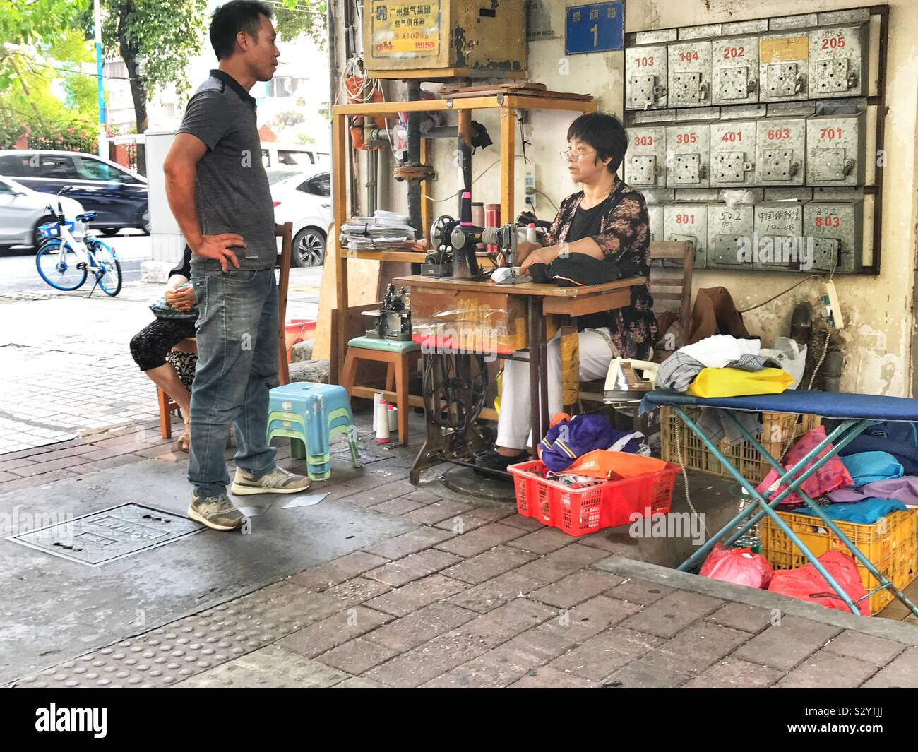 Outdoor tailor: A Chinese tailor with her sewing machine for mending ...