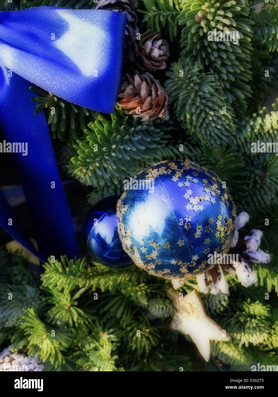 Blue bauble and blue ribbon on Christmas tree. Soft “Orton” effect ...
