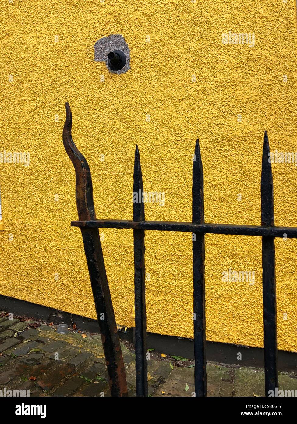 Railings against yellow roughcast wall with boiler vent Stock Photo - Alamy