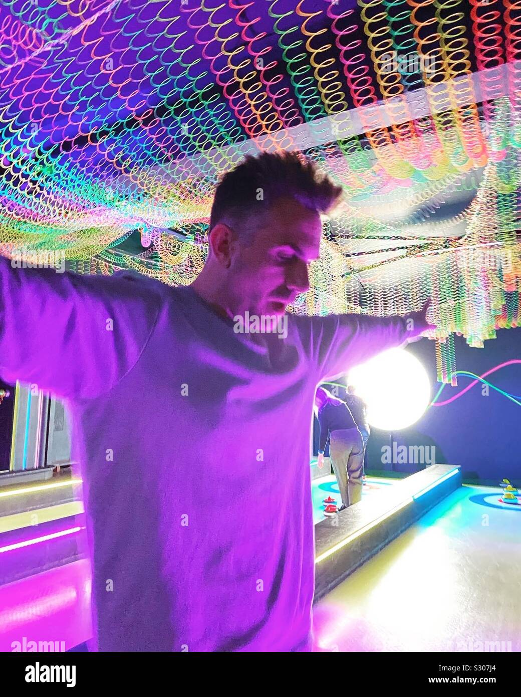 Man with arms outstretched with curling lanes in the background and ...