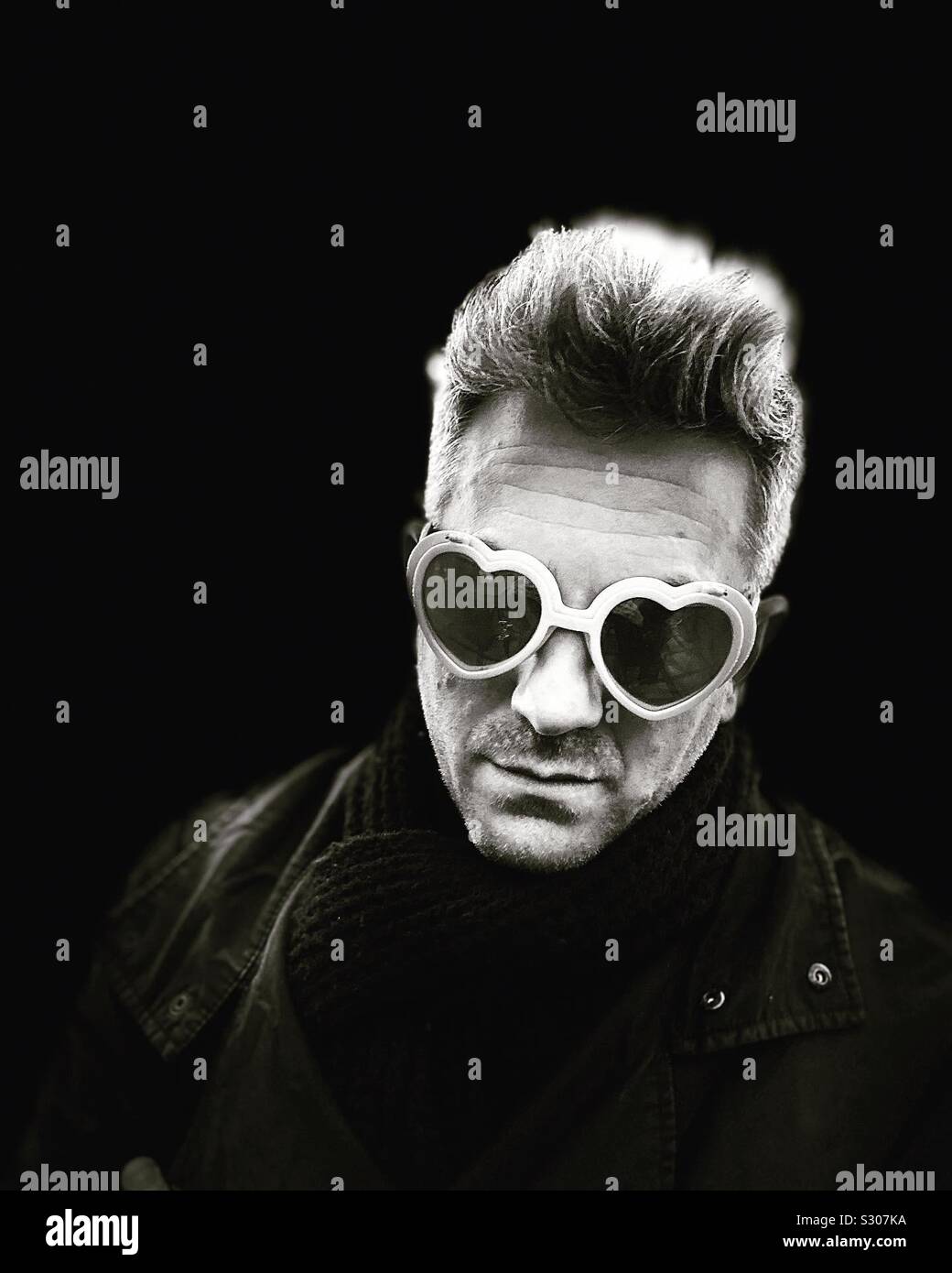 Grumpy looking man in monochrome wearing heart shaped sun glasses Stock ...