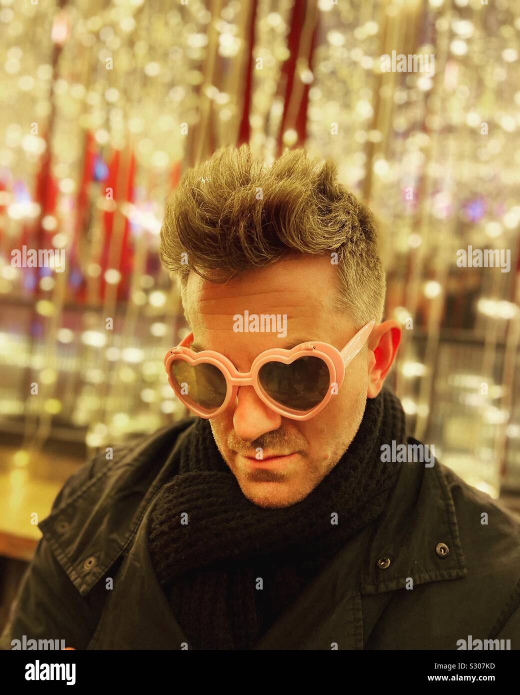 Grumpy looking man in pink heart shaped sunglasses with twinkly ...