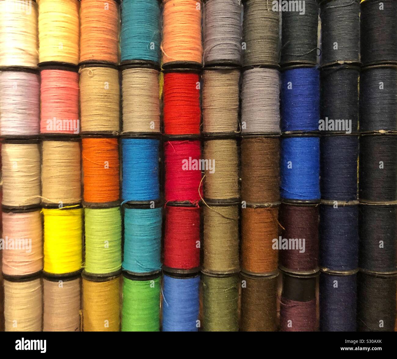 A closeup photo of many spools of colorful thread aligned in rows Stock ...