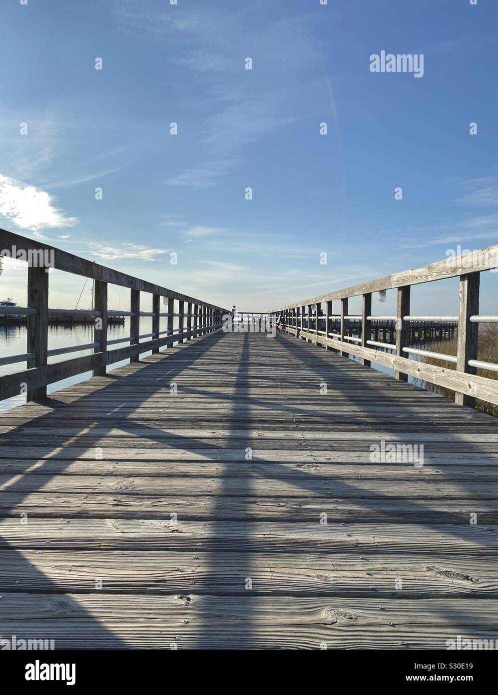 Perspective on long wooden pier over bay water Stock Photo - Alamy