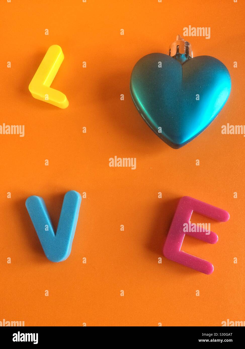 Love word made with colorful letters and blue shining heart on orange ...