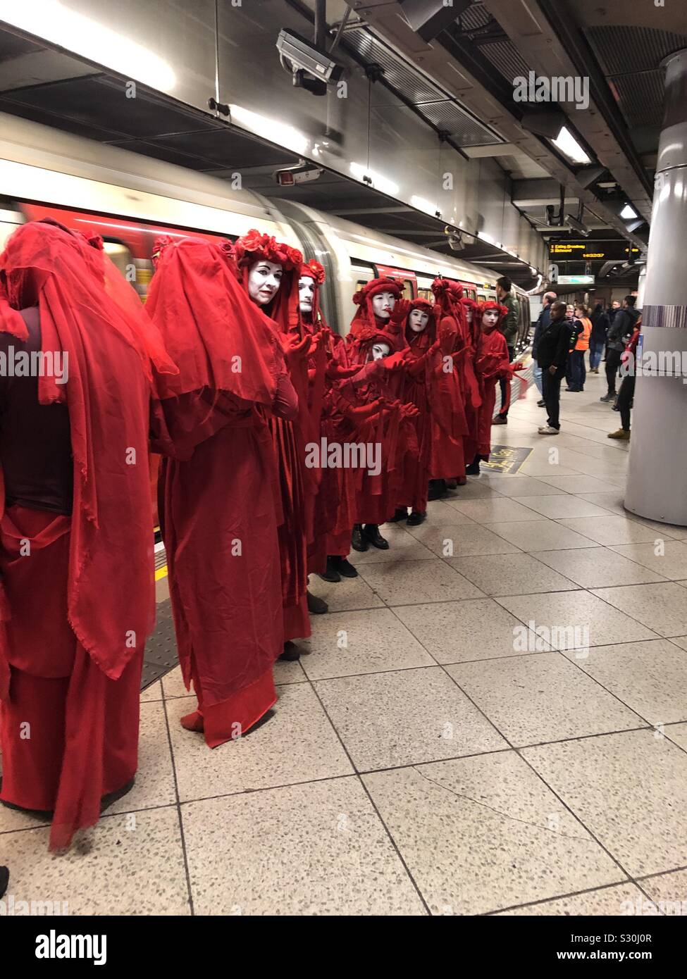 The Red Brigade of Extinction Rebellion on an underground station Stock ...