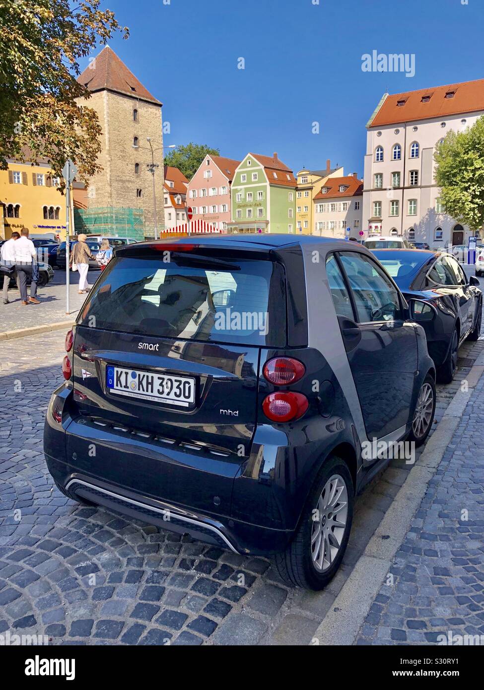 Smart Car and other cars parked along a cobblestone street with ...