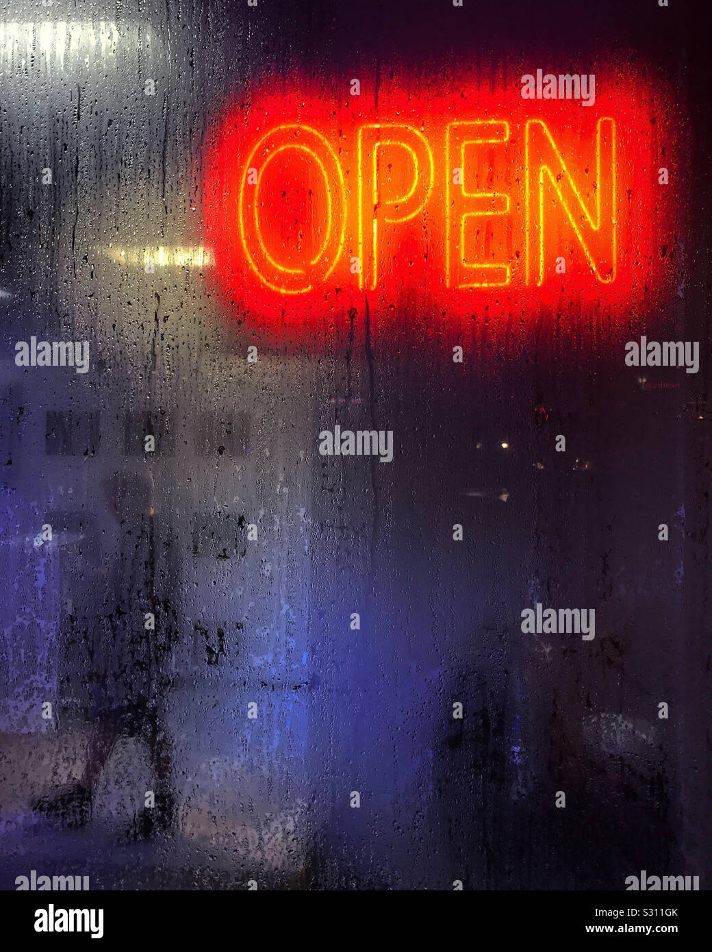 Silhouette of man in front of shop window with a fluorescent Open sign ...