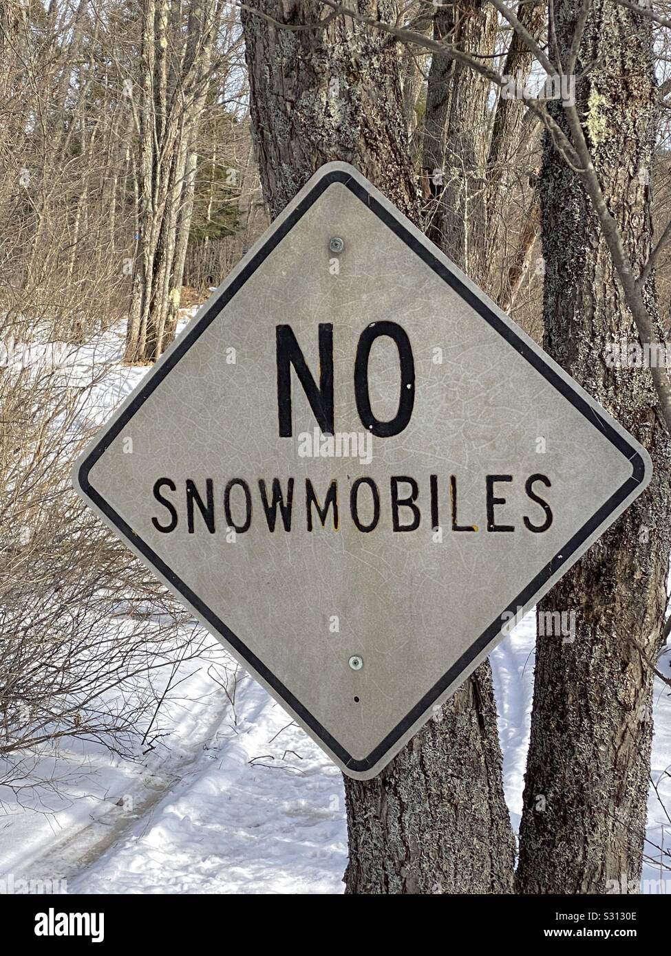 An old weathered and faded “No snowmobiles “ sign on a cross country ...