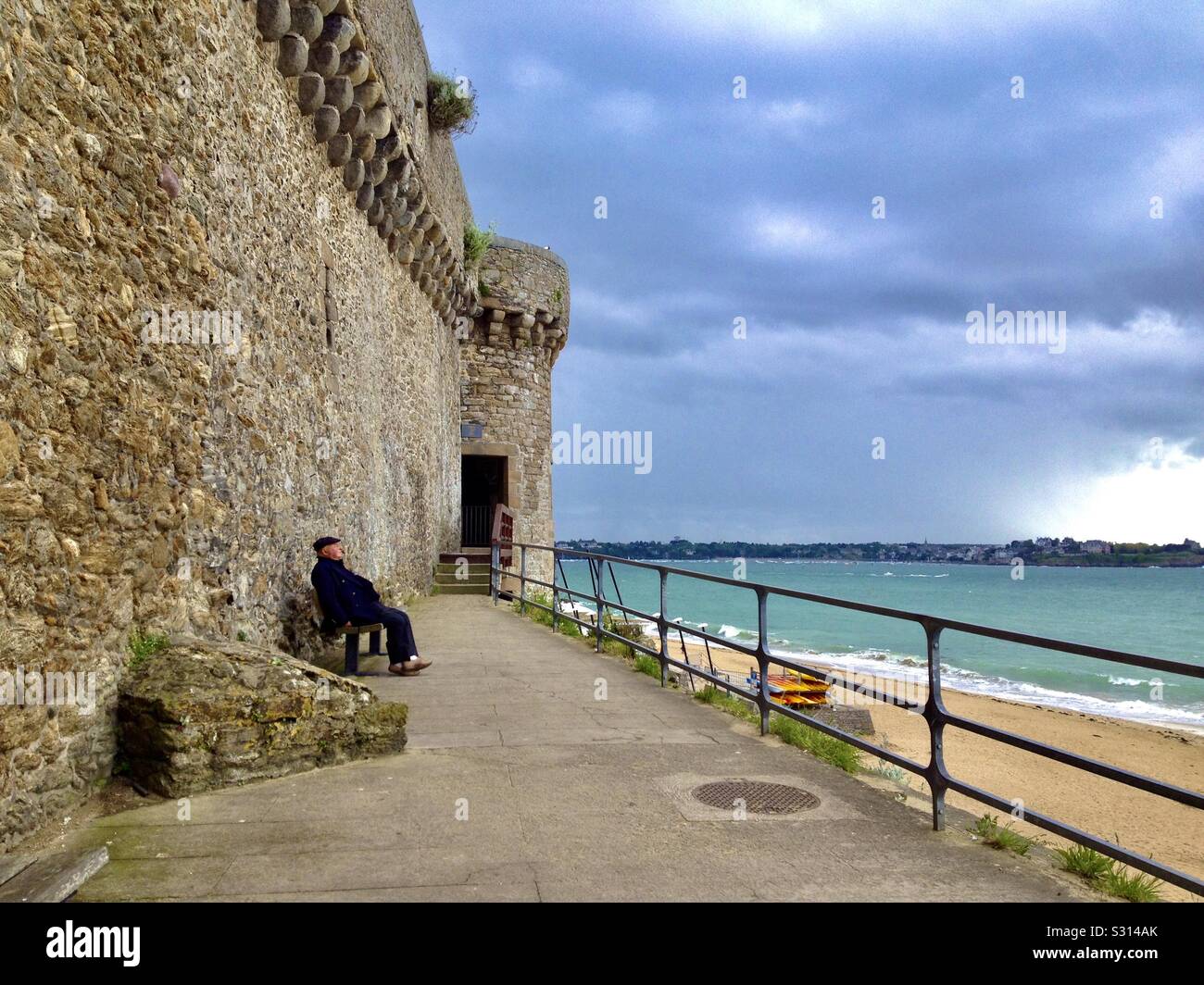 Frenchman sitting and enjoying the ocean view from a bench by Fort ...